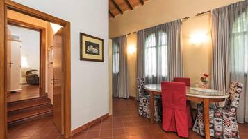 Uma sala de jantar com mesa e cadeiras, uma escada e um quadro na parede.