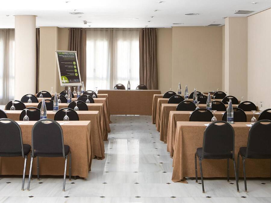 Uma sala de conferência com mesas e cadeiras dispostas em fileiras, um pódio e um banner na parede.
