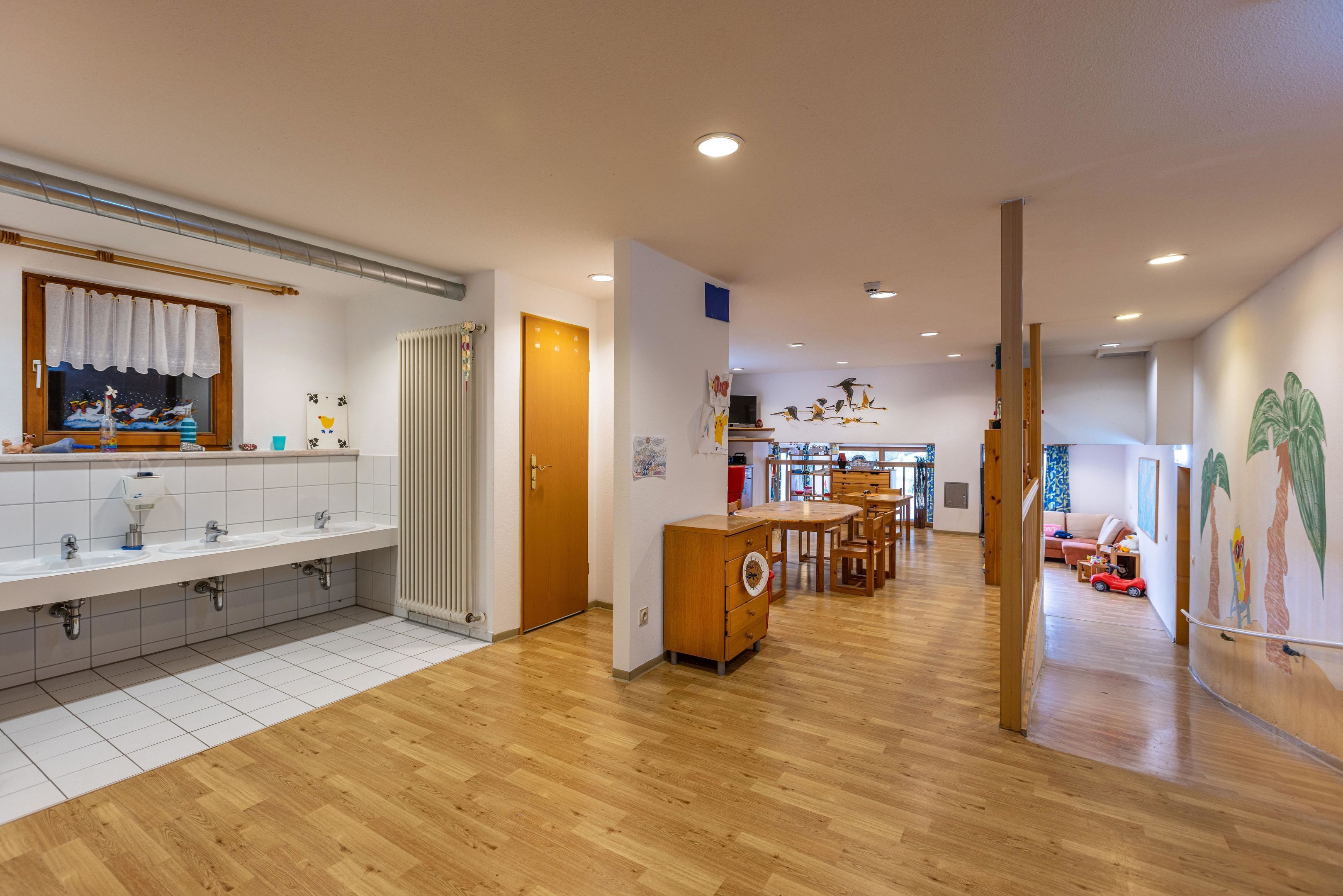 Uma cozinha moderna com armários de madeira, área de jantar com mesa e cadeiras, e um corredor que dá para uma sala de estar.