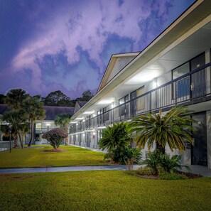 Um hotel moderno com área externa coberta, várias varandas e paisagismo exuberante.