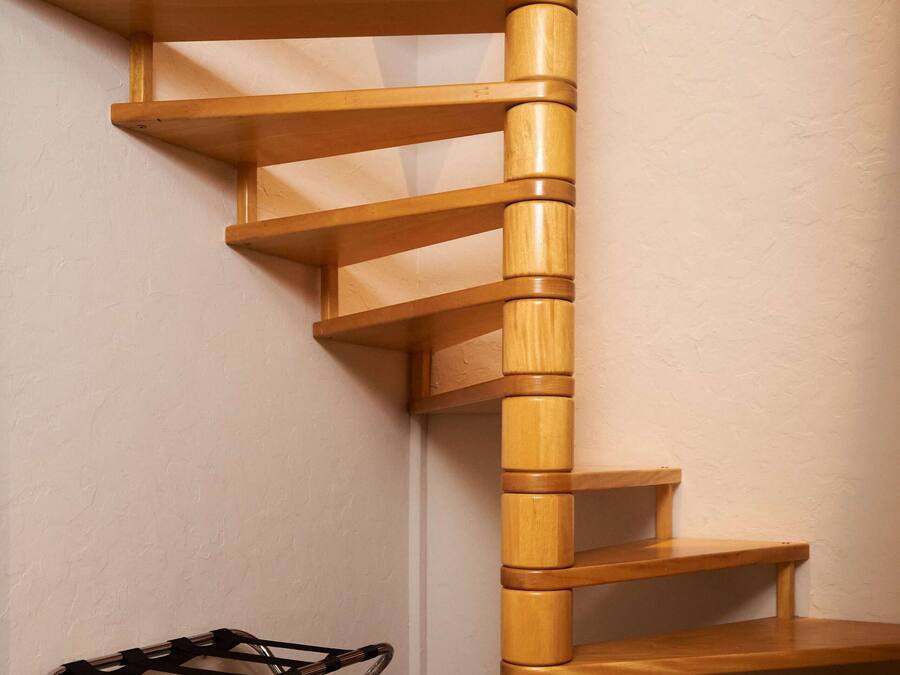 Uma escada de madeira em espiral com uma escada de metal na base.