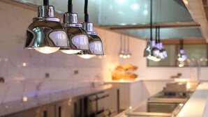 Uma cozinha moderna com luminárias pendentes, eletrodomésticos de aço inoxidável e painel de vidro.