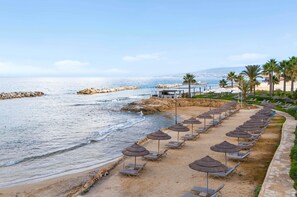 Na praia, espreguiçadeiras, guarda-sóis, toalhas de praia 