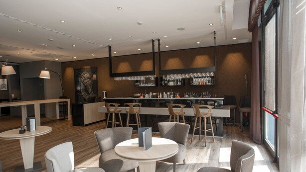 Uma área de bar moderna, com balcão, assentos e uma grande janela.