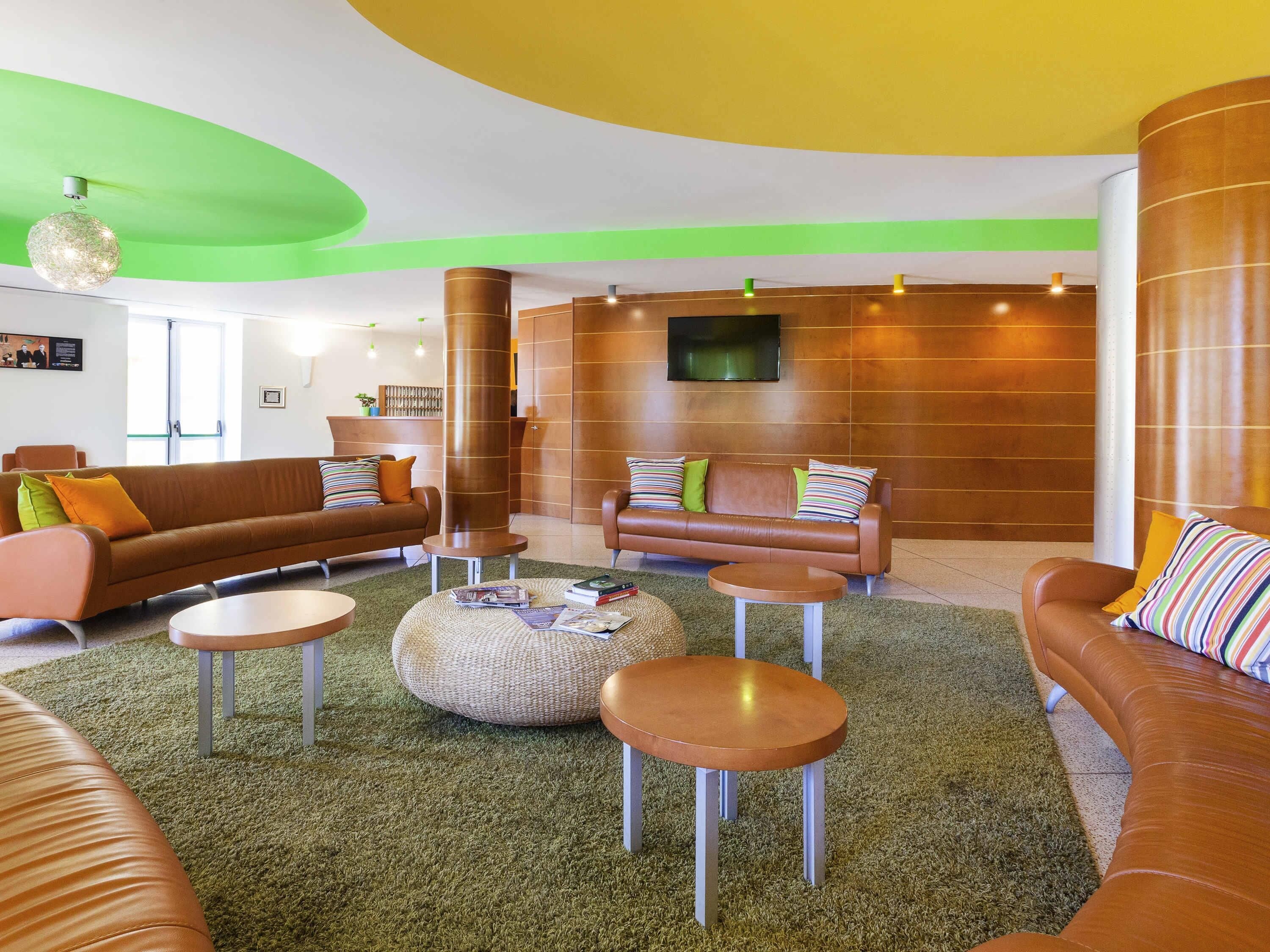Uma sala de estar moderna com sofás de couro, mesas de centro redondas e um tapete verde.