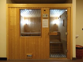 Uma sala de sauna de madeira com um banco, um painel de controle e uma placa com instruções.