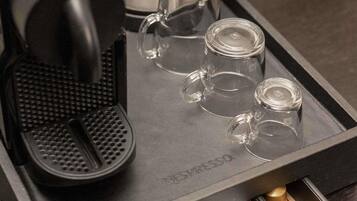 Uma máquina de café e quatro copos de vidro sobre uma bandeja.