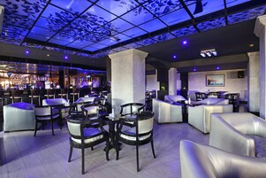 Uma área de lounge moderna com bar, assentos e teto com padrão floral.