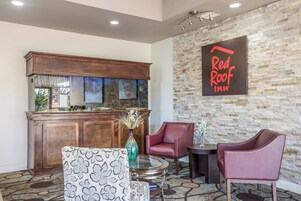 Lobby do Red Roof Inn com parede de pedra, balcão de madeira e área de estar.