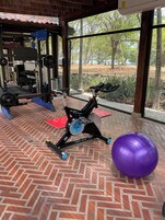 Uma academia com equipamento de exercícios, uma janela grande e um padrão de piso em herringbone.