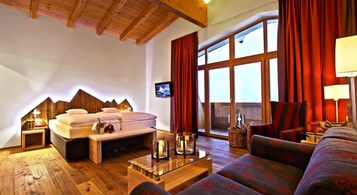Um quarto acolhedor com cama, sofá, mesa de centro e televisão.