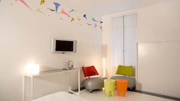 Quarto moderno com cama, escrivaninha, televisão e decorações coloridas nas paredes.