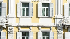 Um edifício amarelo com detalhes brancos e molduras decorativas.