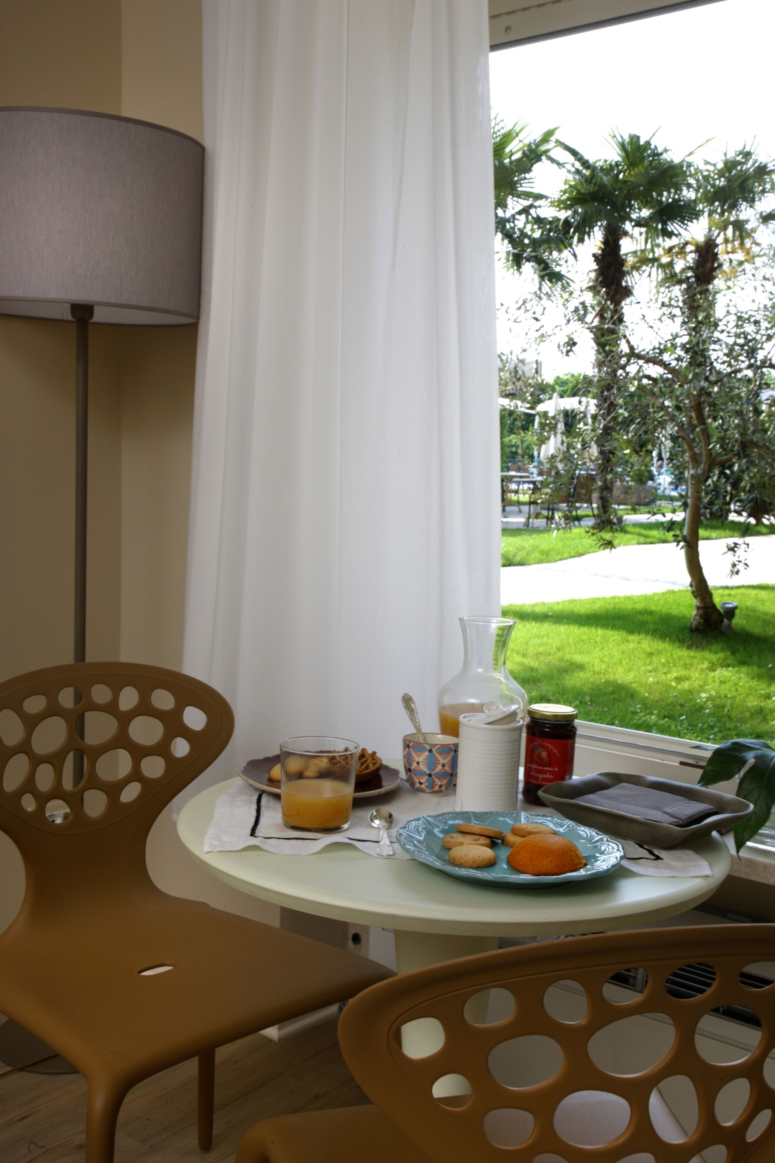 Uma área de refeições com uma mesa posta para o café da manhã, incluindo um prato de biscoitos e um copo de suco de laranja.