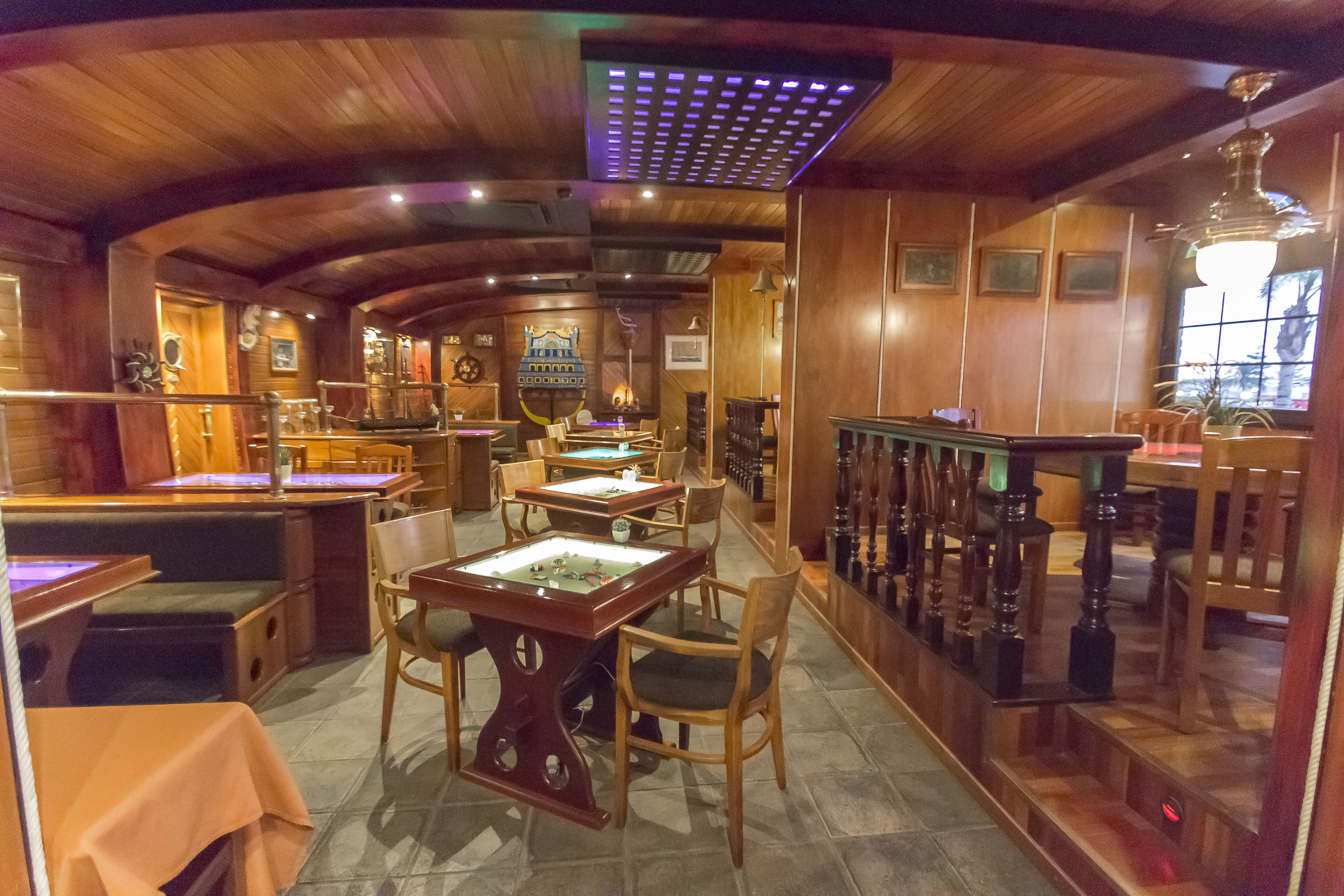 Um quarto com lambris de madeira, mesa de bilhar e várias áreas de estar.