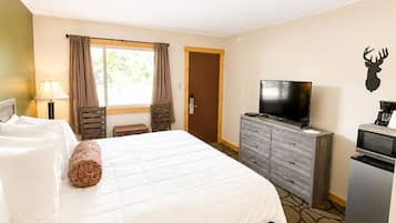Quarto de hotel com cama, televisão, escrivaninha com cafeteira e um chifre de veado fixado na parede.