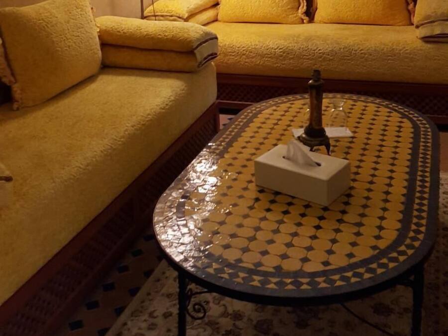 Um quarto acolhedor com um sofá, uma mesa de centro estampada e um abajur.