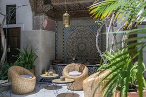 Uma área externa com mobiliário de vime e um painel decorativo revestido de azulejos.