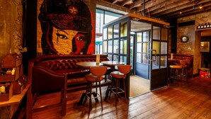 Um restaurante acolhedor com decoração em madeira, um grande mural e vários tipos de assentos, incluindo um banco e banquetas.