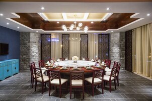 Uma sala de jantar formal com uma mesa redonda, cadeiras de madeira e um lustre.