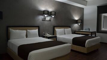 Quarto de hotel com duas camas, uma mesa e uma cadeira.