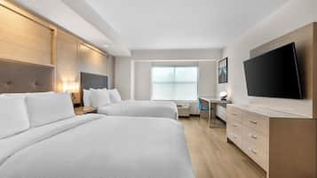 Quarto de hotel com duas camas, uma mesa, televisão de tela plana e uma janela.
