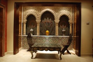 Um interior tradicional com parede estampada, uma mesa central e duas cadeiras.