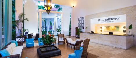 Um hall amplo com poltronas azuis, um balcão de recepção e uma janela grande com vista para o exterior.