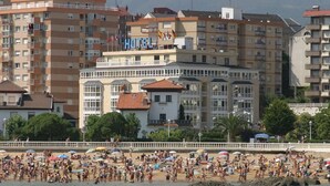 Um hotel com vários andares, varandas e uma praia ao primeiro plano.