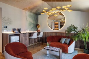 Uma sala de estar moderna com sofá, cadeiras, mesa de centro, área de cozinha e um espelho grande.
