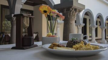 Uma mesa de jantar com um prato de comida, um vaso de flores e um castiçal.