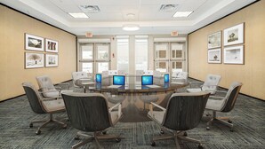 Uma sala de conferências com uma mesa de vidro, seis cadeiras e laptops.