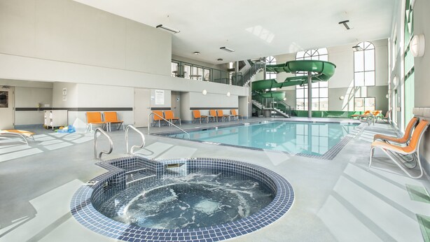 Uma piscina interior ampla com hidromassagem, espreguiçadeiras e um toboágua.