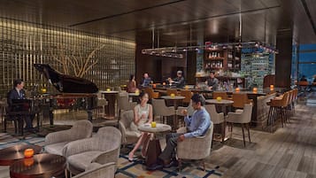 Uma área de bar moderna com piano, assentos e um bartender.