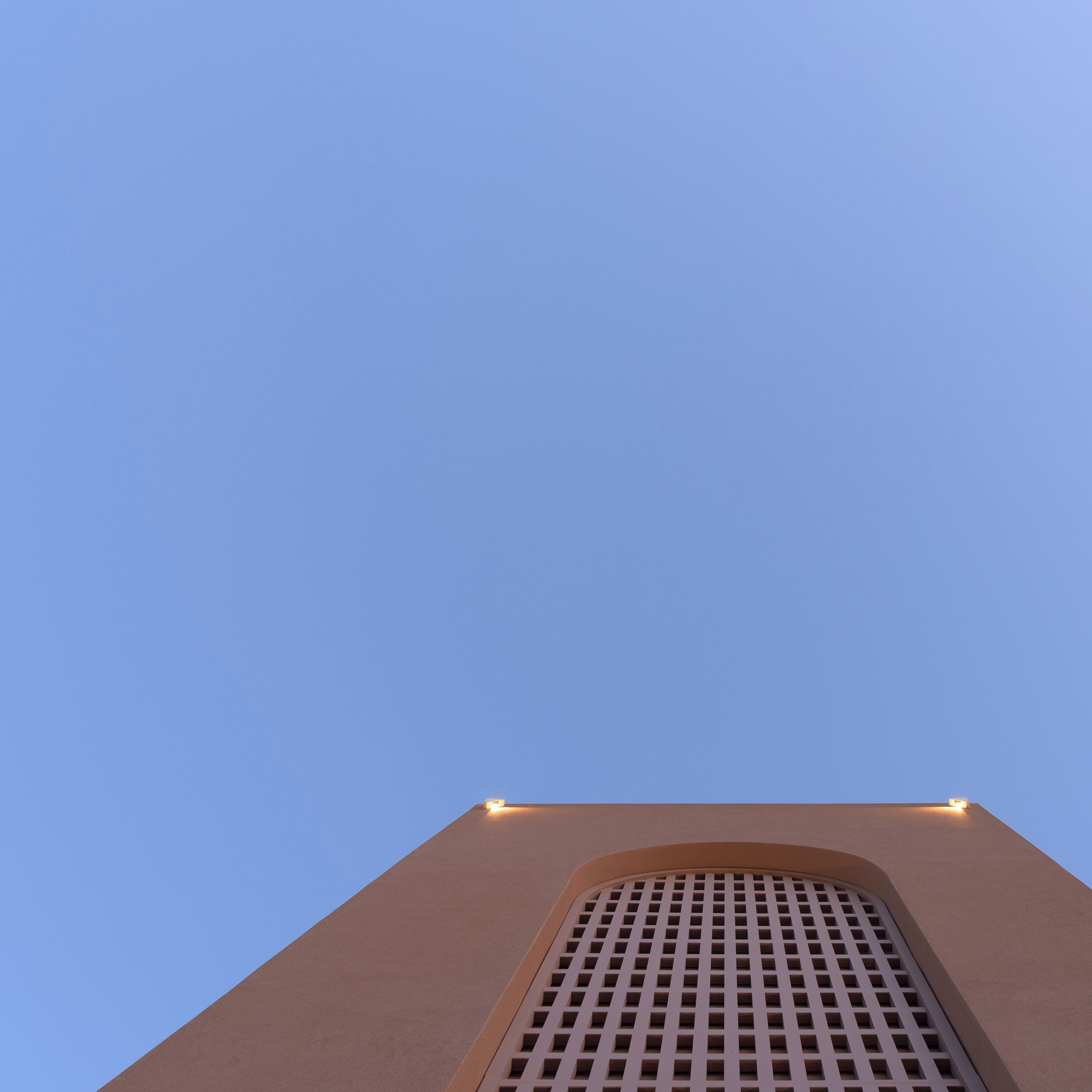 Um edifício alto com fachada em grade e borda superior curva.