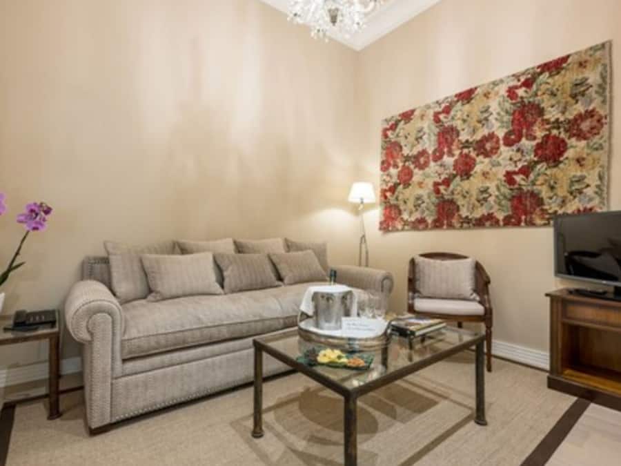 Uma sala de estar com sofá, mesa de centro, rack para TV e um quadro floral na parede.