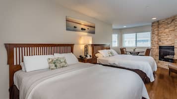 Quarto de hotel com duas camas, lareira de pedra, mesa de jantar e um quadro na parede.