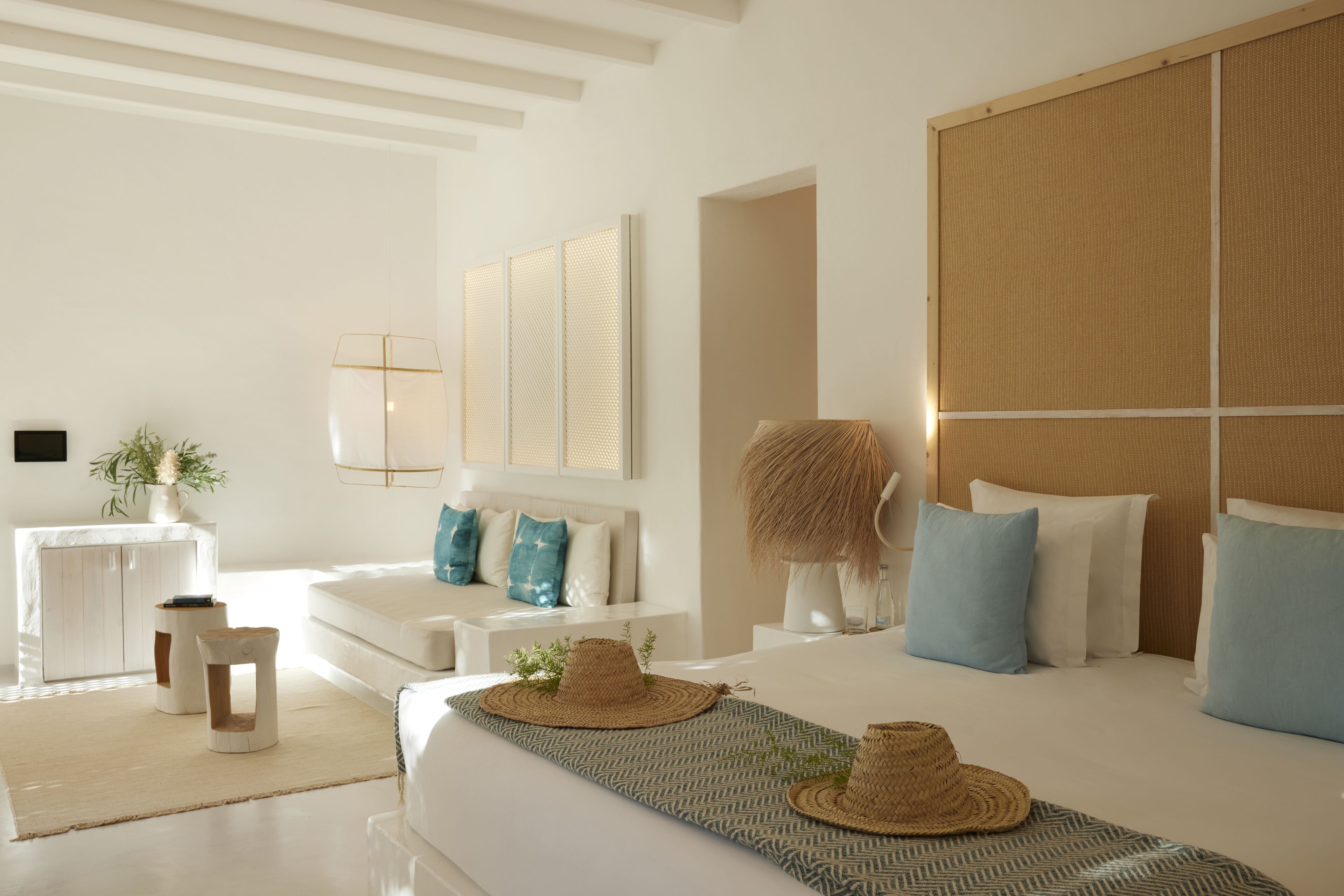 Quarto de hotel moderno com uma cama grande, um sofá, uma mesinha e um painel decorativo na parede.