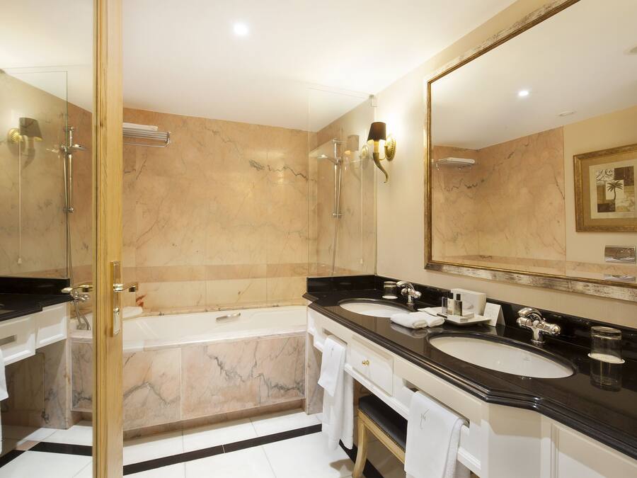 Casa de banho moderna com duas pias, banheira e cabine de chuveiro com vidro.