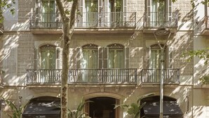 Um hotel com vários andares e estilo arquitetônico clássico, com varandas com grades de ferro forjado e grandes janelas com persianas.