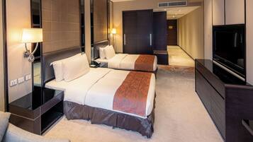 Quarto de hotel com duas camas, televisão, secretária e uma cadeira.