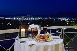 Mesa posta para dois com vista para a cidade à noite.