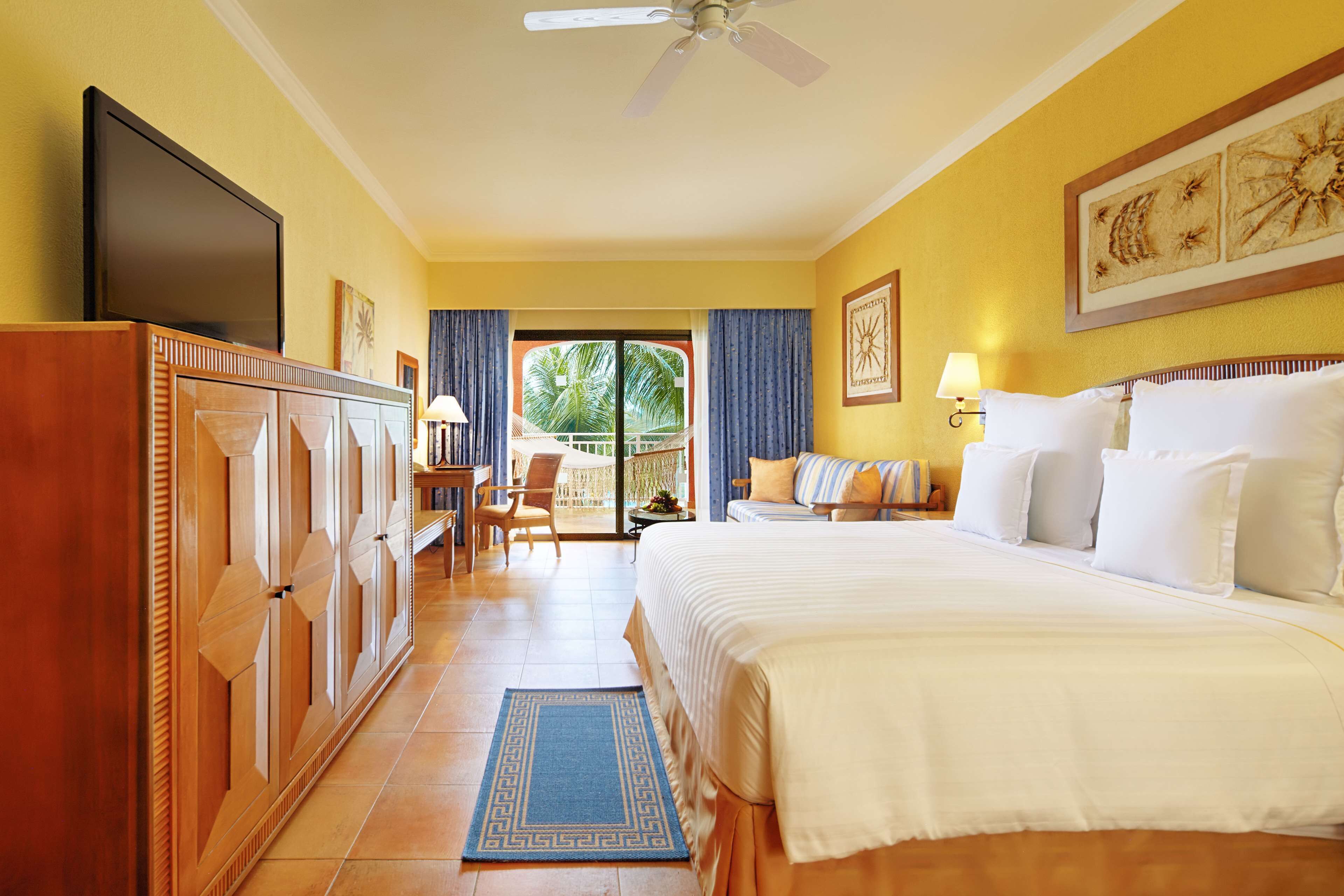 Quarto de hotel com cama, escrivaninha, televisão e vista para o exterior.