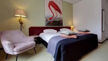 Quarto de hotel com cama, cadeira, luminária e pintura na parede.