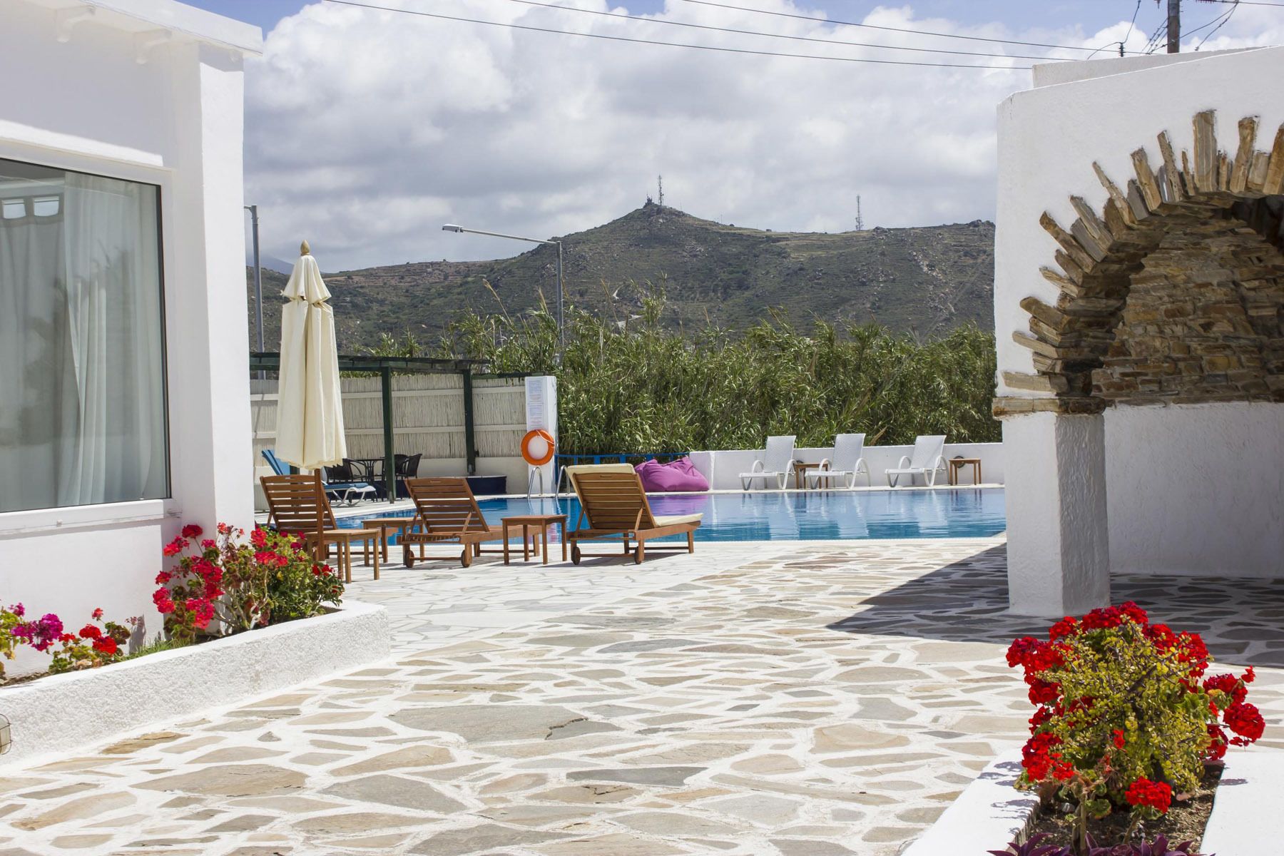 Área de piscina com piso de pedra, espreguiçadeiras e vista para uma montanha.