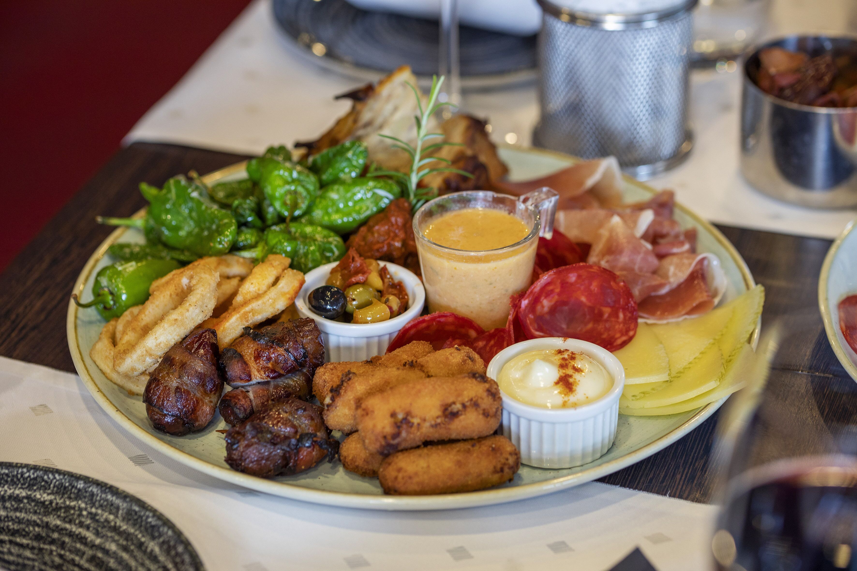 Prato com variedade de alimentos, incluindo carnes, legumes e um pequeno recipiente com molho.
