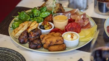 Prato com variedade de alimentos, incluindo carnes, legumes e um pequeno recipiente com molho.