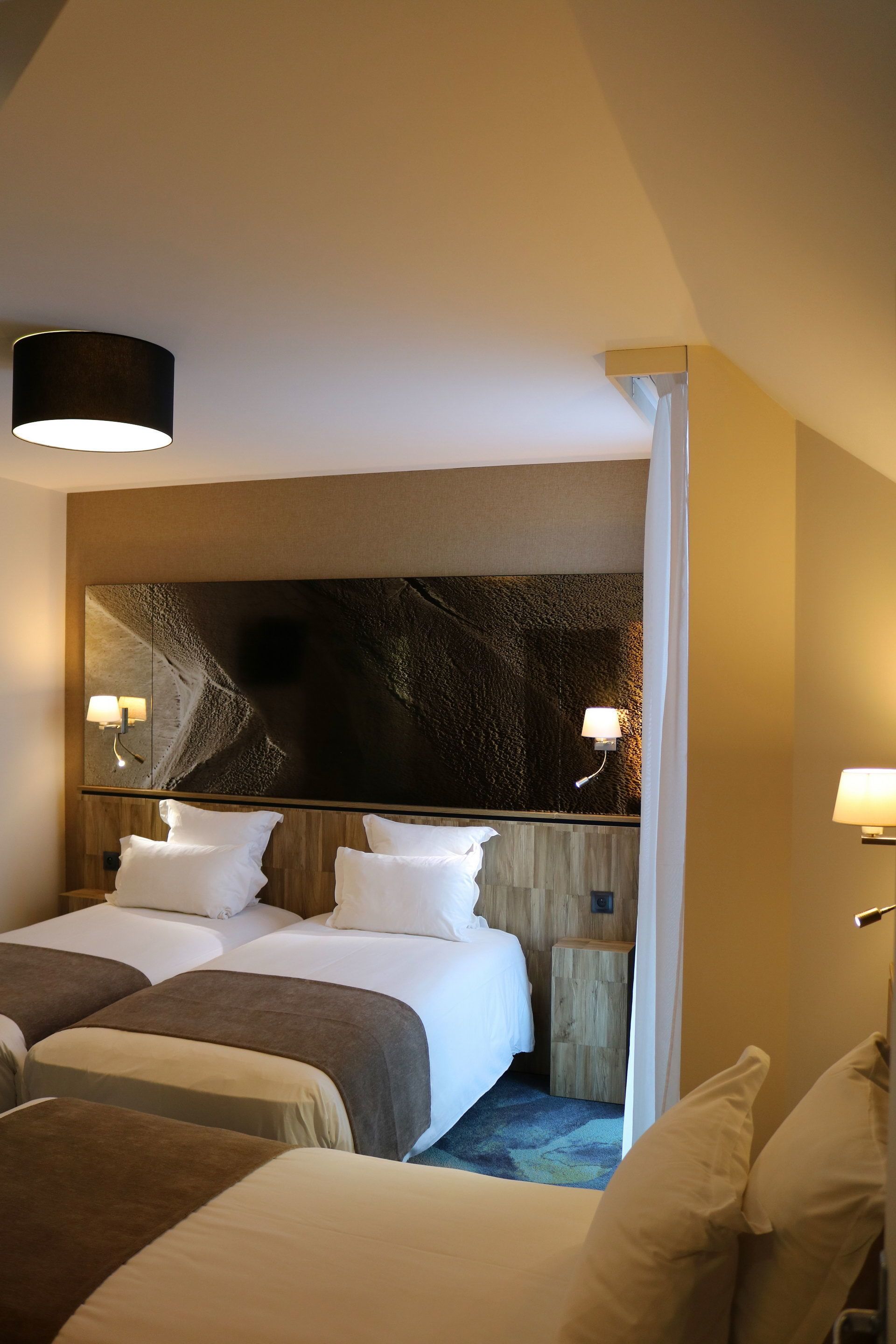 Quarto de hotel com duas camas, um espelho grande e uma cabeceira de madeira.