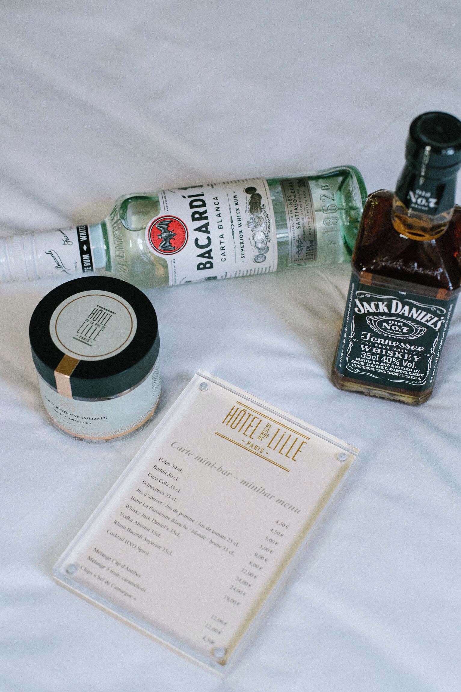 Uma garrafa de uísque Jack Daniel's Tennessee, um pote de caramelos e um cardápio sobre uma superfície branca.