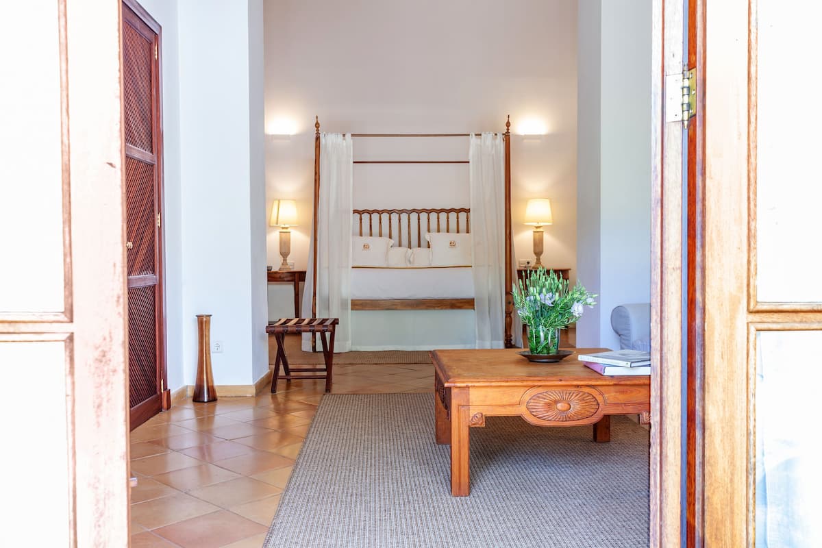 Quarto com uma cama, uma mesa de madeira, uma cadeira e um abajur.